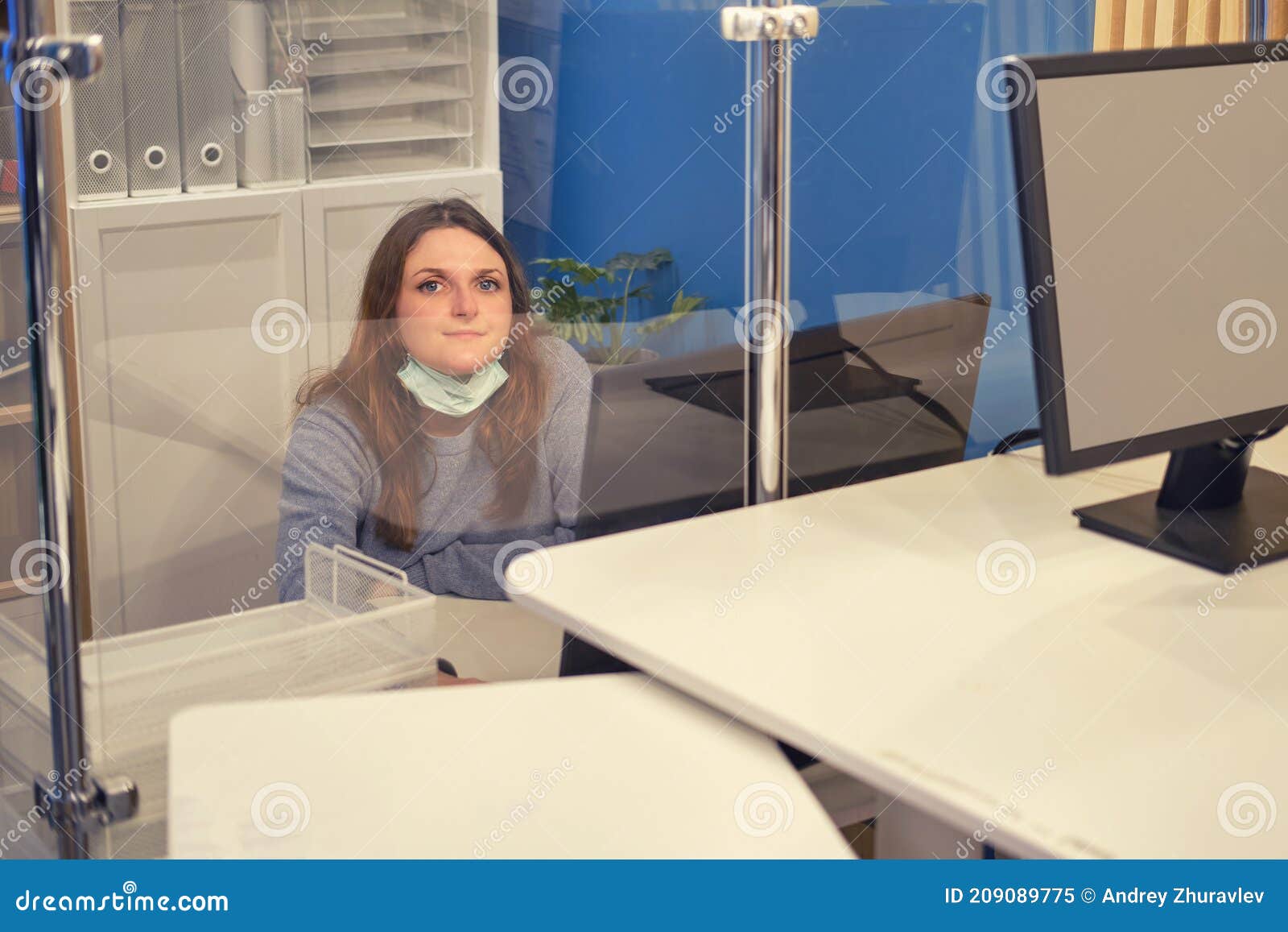 Office Worker in Face Mask at Computer in a Room with Protective Glass ...