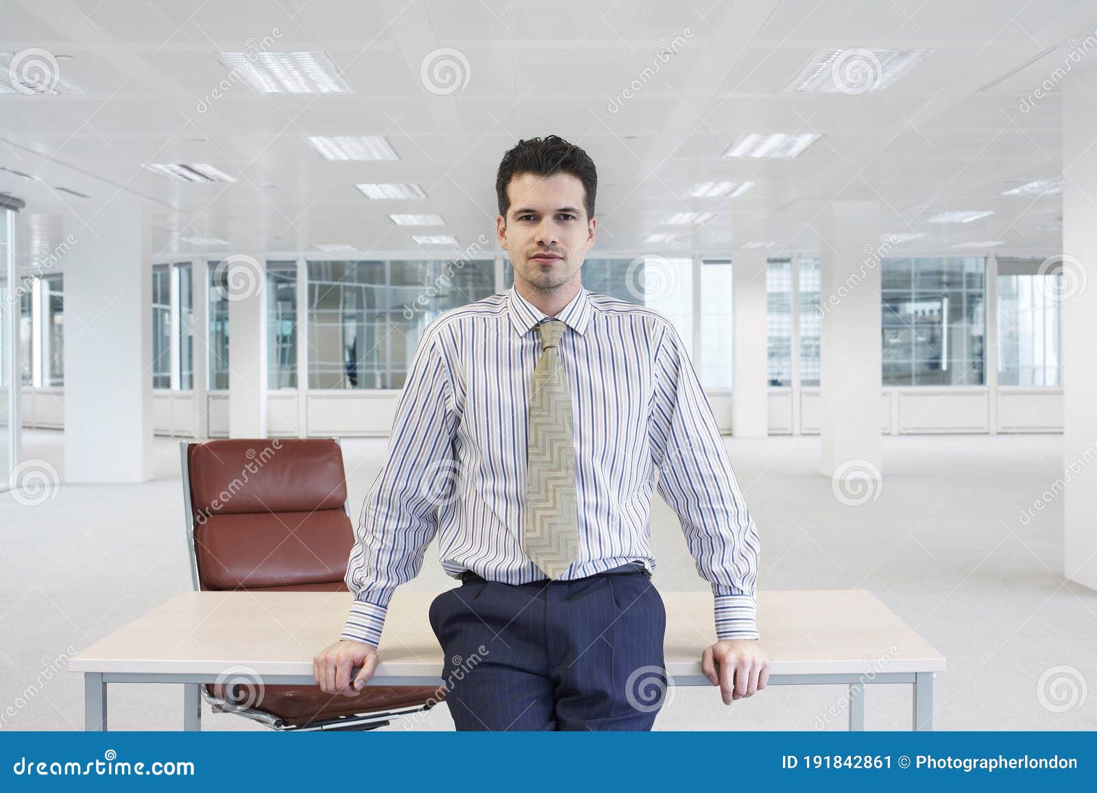 Office Worker Perching on Edge of Table in Empty Office Space Stock ...