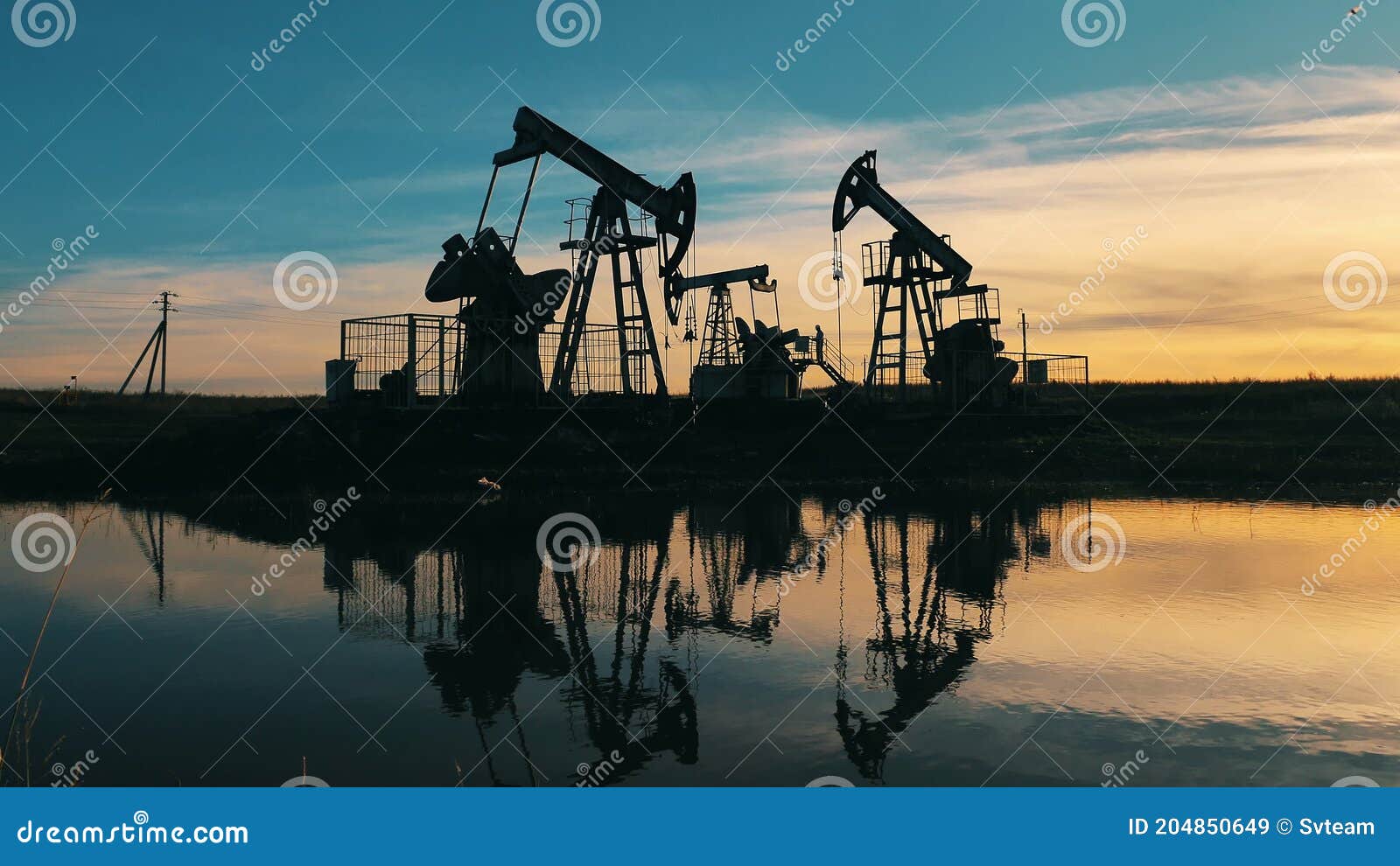 Oil Pumping Units Operating at Sunset, Reflected on Water Surface Stock ...