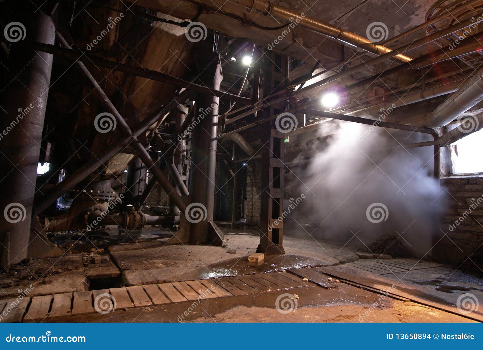 DECAYING FACTORY BUILDING ROOF BEHIND A SECURITY FENCE AND RAILWAY ...