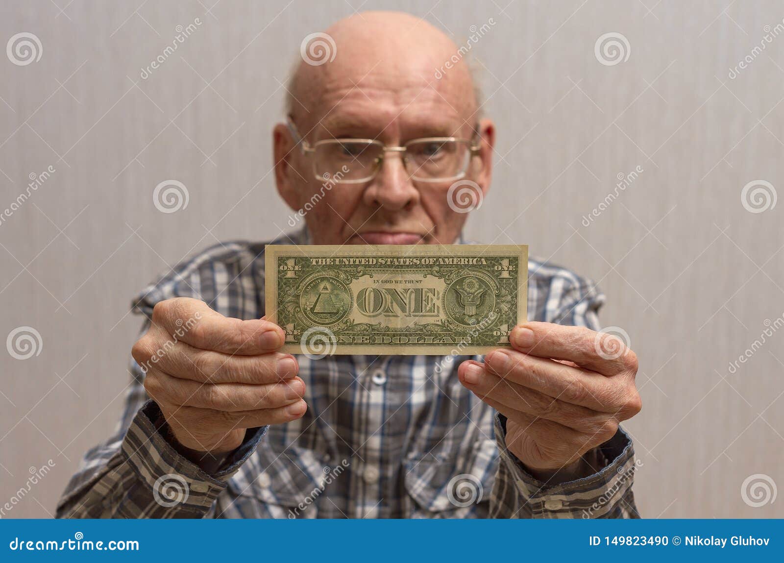 An Old Bald Man with Glasses Holds a Banknote in Front of Him - One US ...
