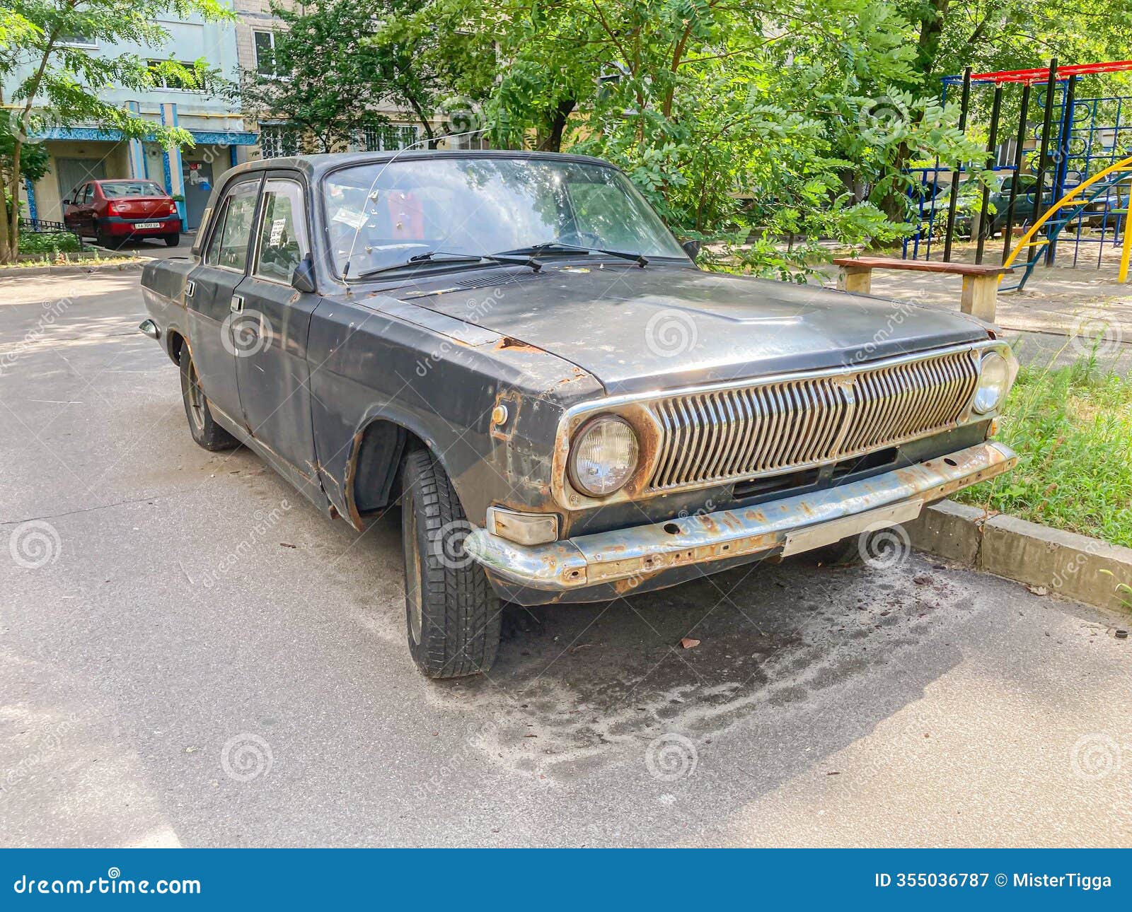 An Old, Battered Car is Parked on a Concrete Surface with Surrounding ...