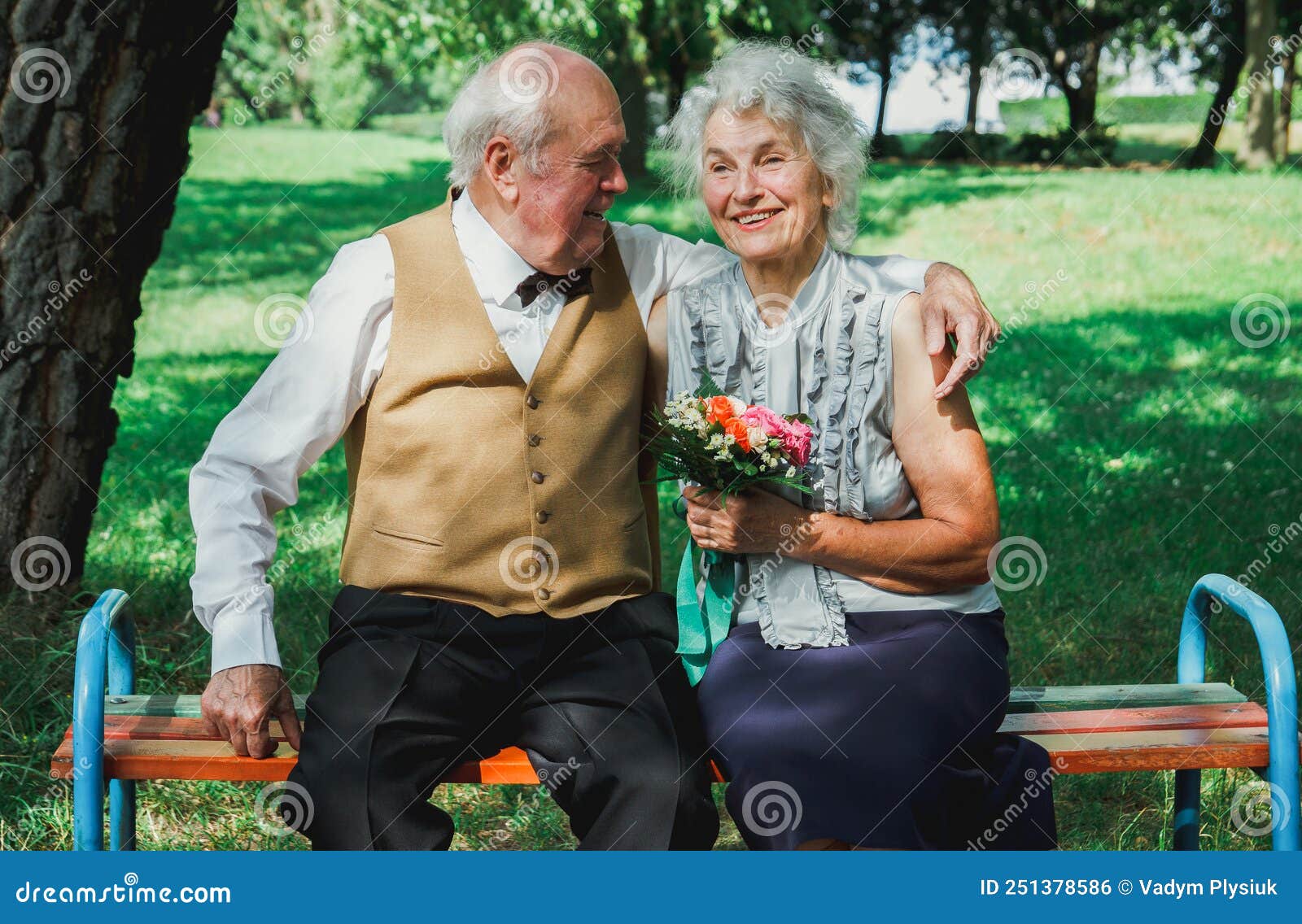 Old Couple Is Sitting On Bench In The Green Park Grandmother And