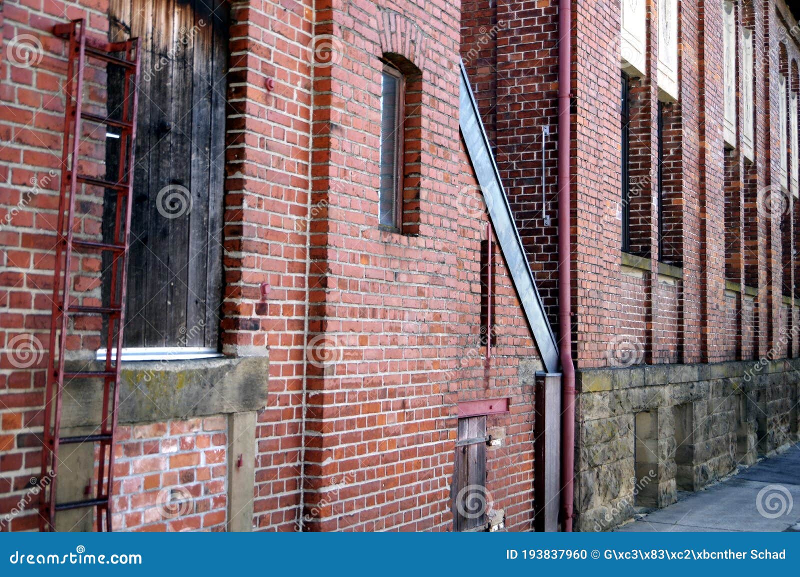 Part of an Old Factory with Brick Wall and Window and a Bent Ladder ...