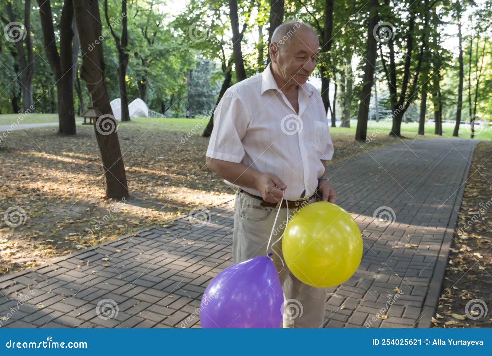 An Old Man is Playing in the Park with Bright, Balloons on His Birthday ...
