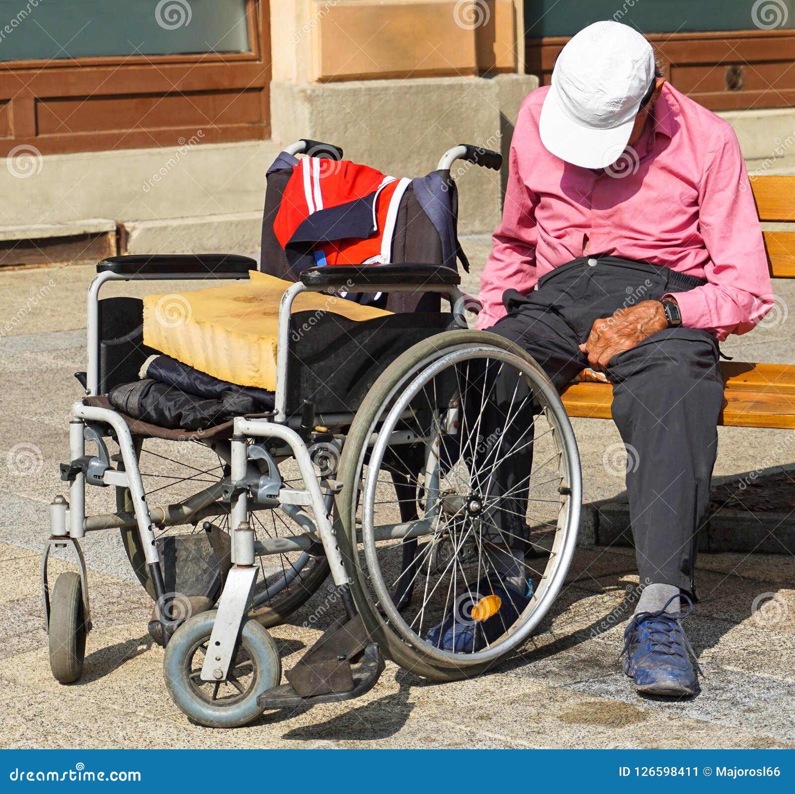 Old Man Sits on a Bench Next To a Wheelchair Stock Image - Image of ...