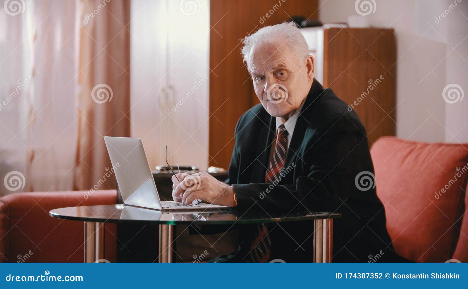 An Old Man Sitting by the Laptop and Looking in the Camera Stock Photo ...