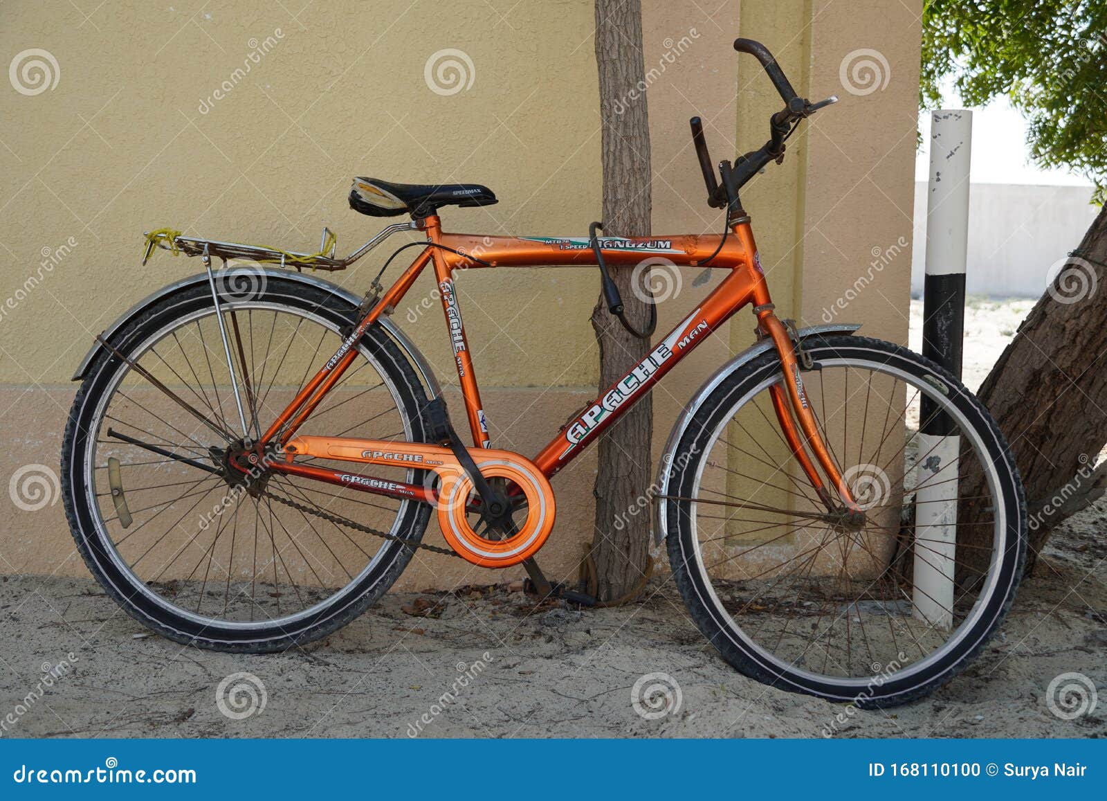 An Old Orange Bicycle Is Standing On The Sand Path Locked To A Tree ...