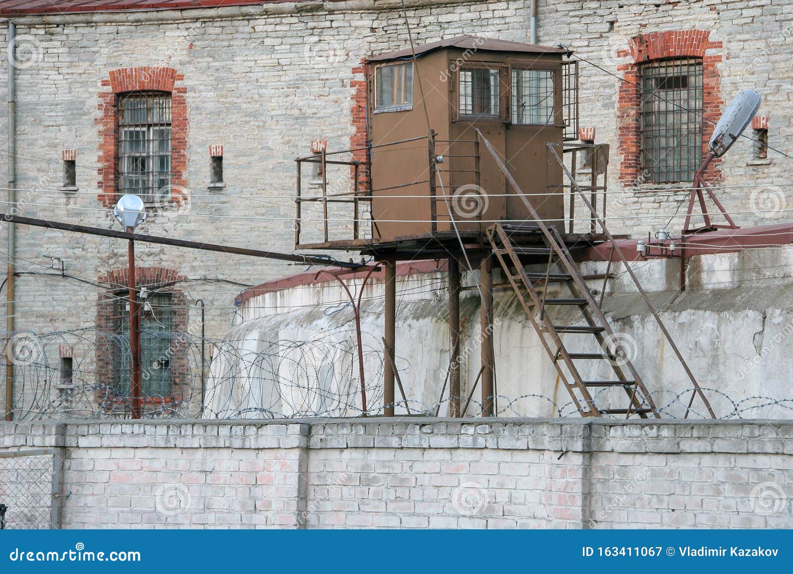 Old Prison Wall with Barbed Wire and Observation Tower Behind it. Stock ...