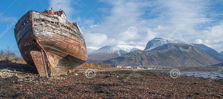 Old Rusty Ship on a Dry Shore with Cloudy Mountains in the Background ...