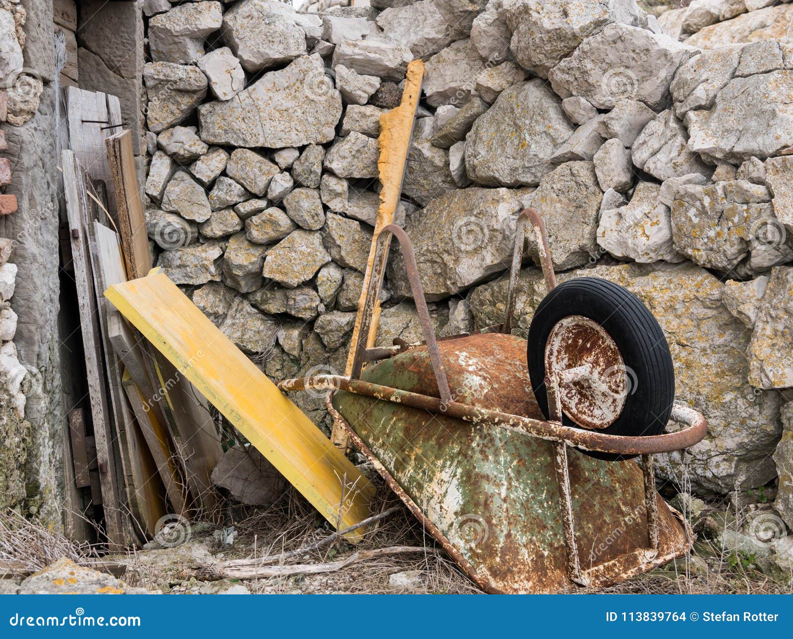 Old Rusty Wheelbarrow Lying on the Floor in Front of Stone Wall Stock ...