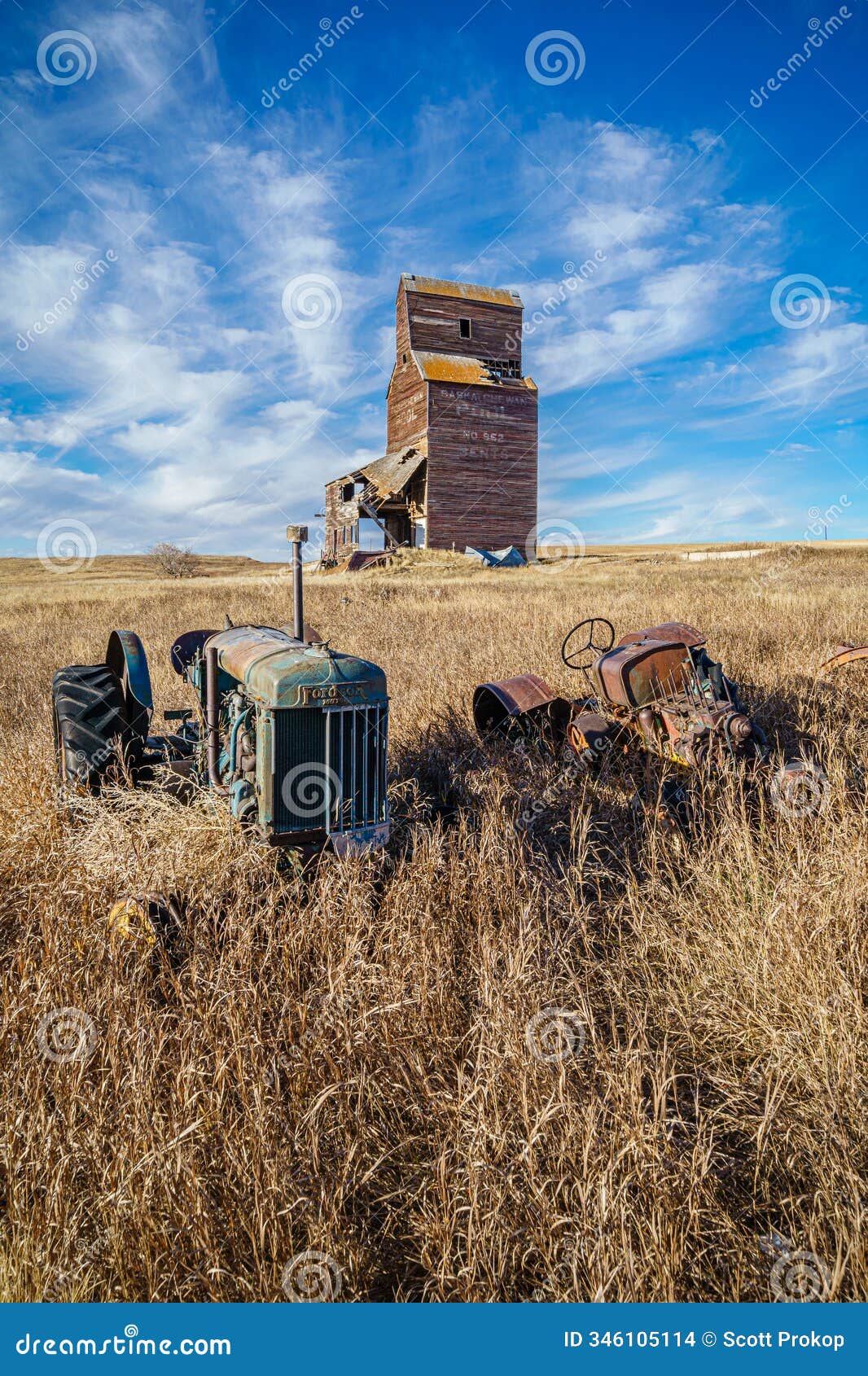 An Old Tractor is Sitting in a Field Next To a Grain Elevator Stock ...