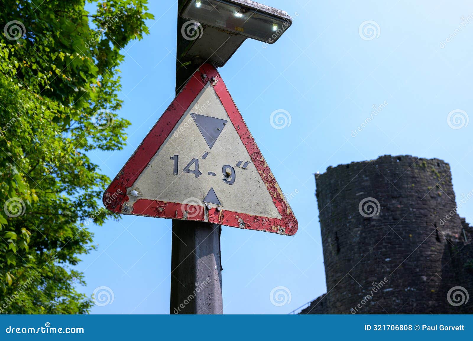 Old Triangular Height Restriction Sign by Stone Tower Under Bright Blue ...