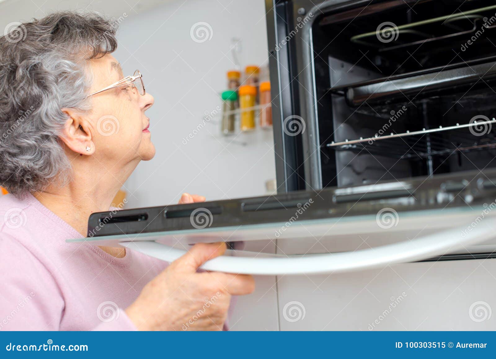 Old woman inspecting oven stock image. Image of oven - 100303515