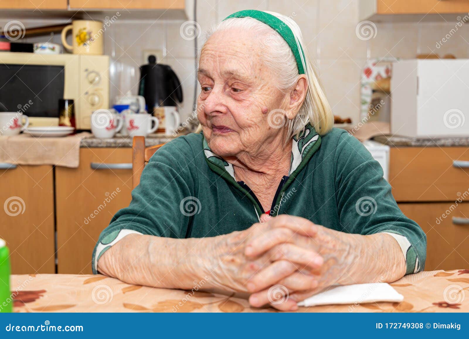 An Old Woman Sitting by the Table at the Kitchen Stock Photo - Image of ...