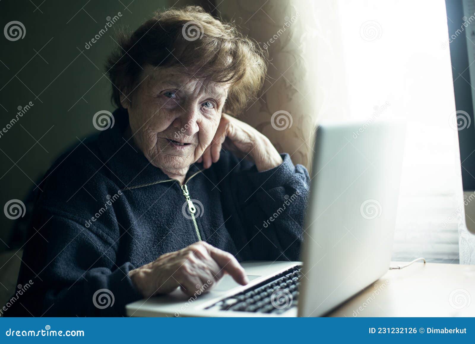 An Old Woman is Study Typing on a Laptop at Her Home. Stock Photo ...