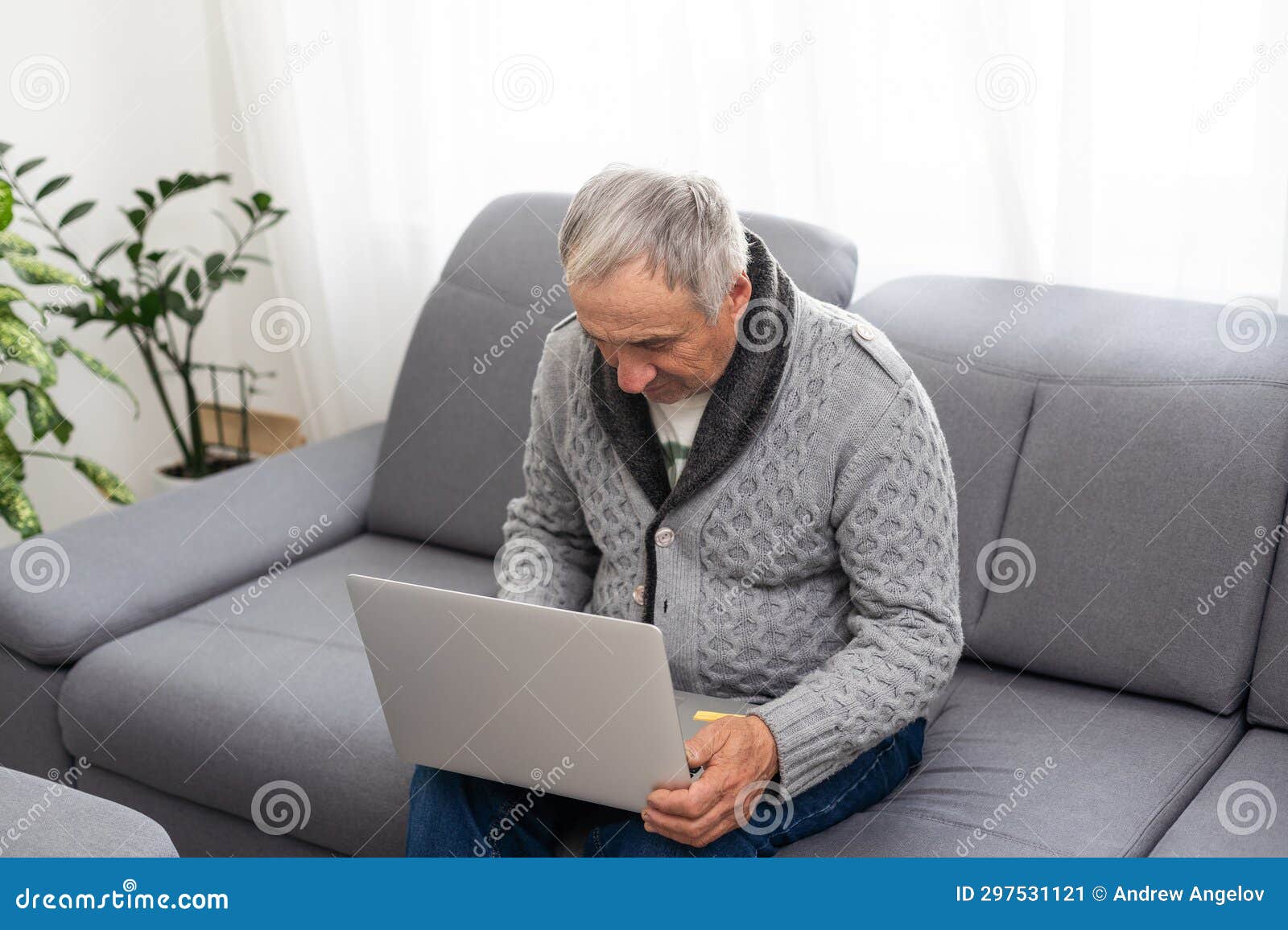 Older Man Sitting on Sofa, Smiling at Computer Screen at Home Stock ...