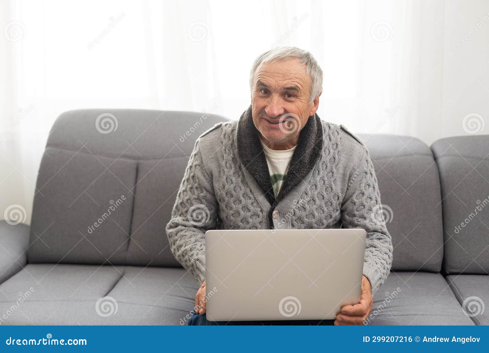 Older Man Sitting on Sofa, Smiling at Computer Screen at Home Stock ...