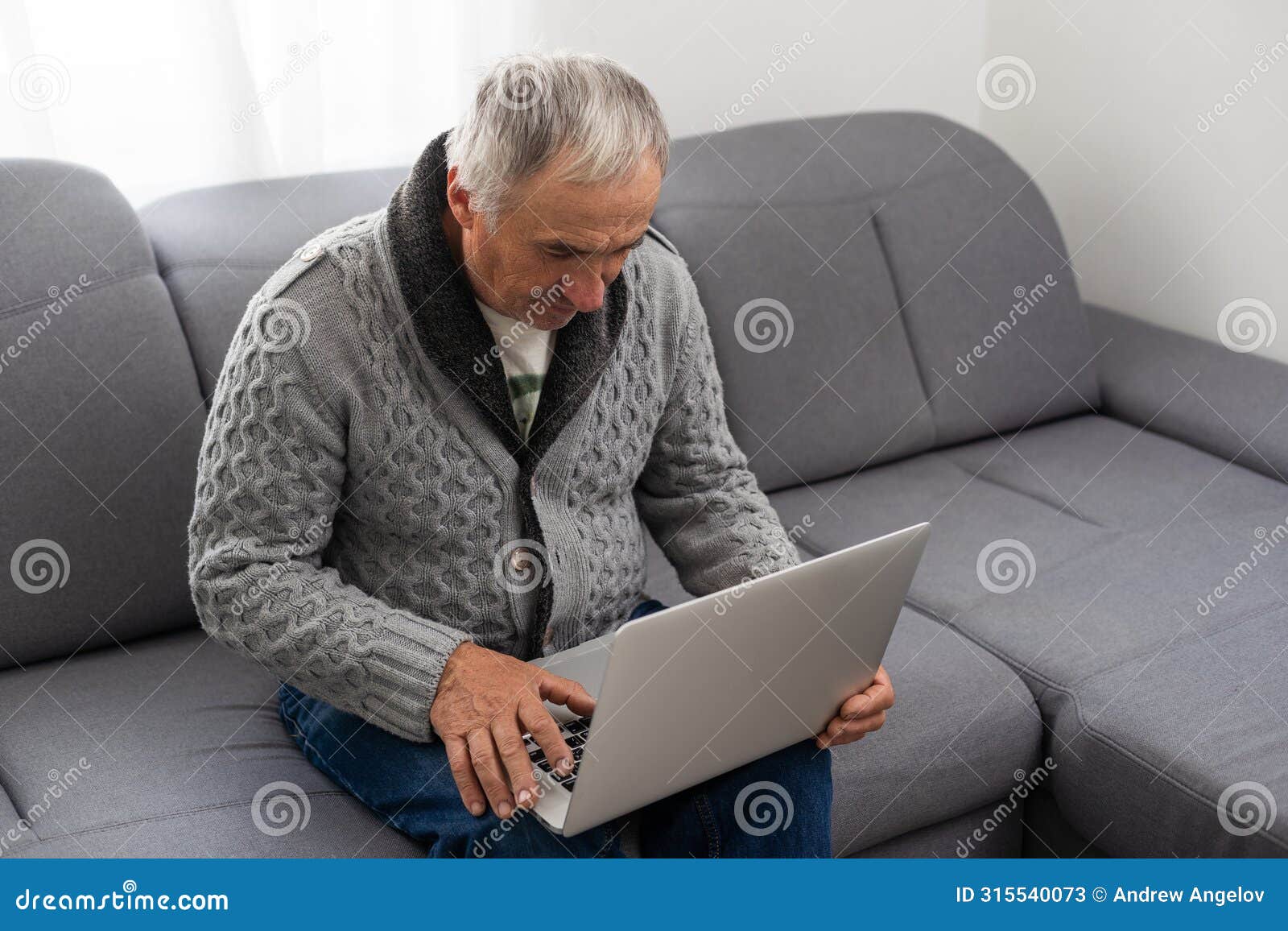 Older Man Sitting on Sofa, Smiling at Computer Screen at Home Stock ...