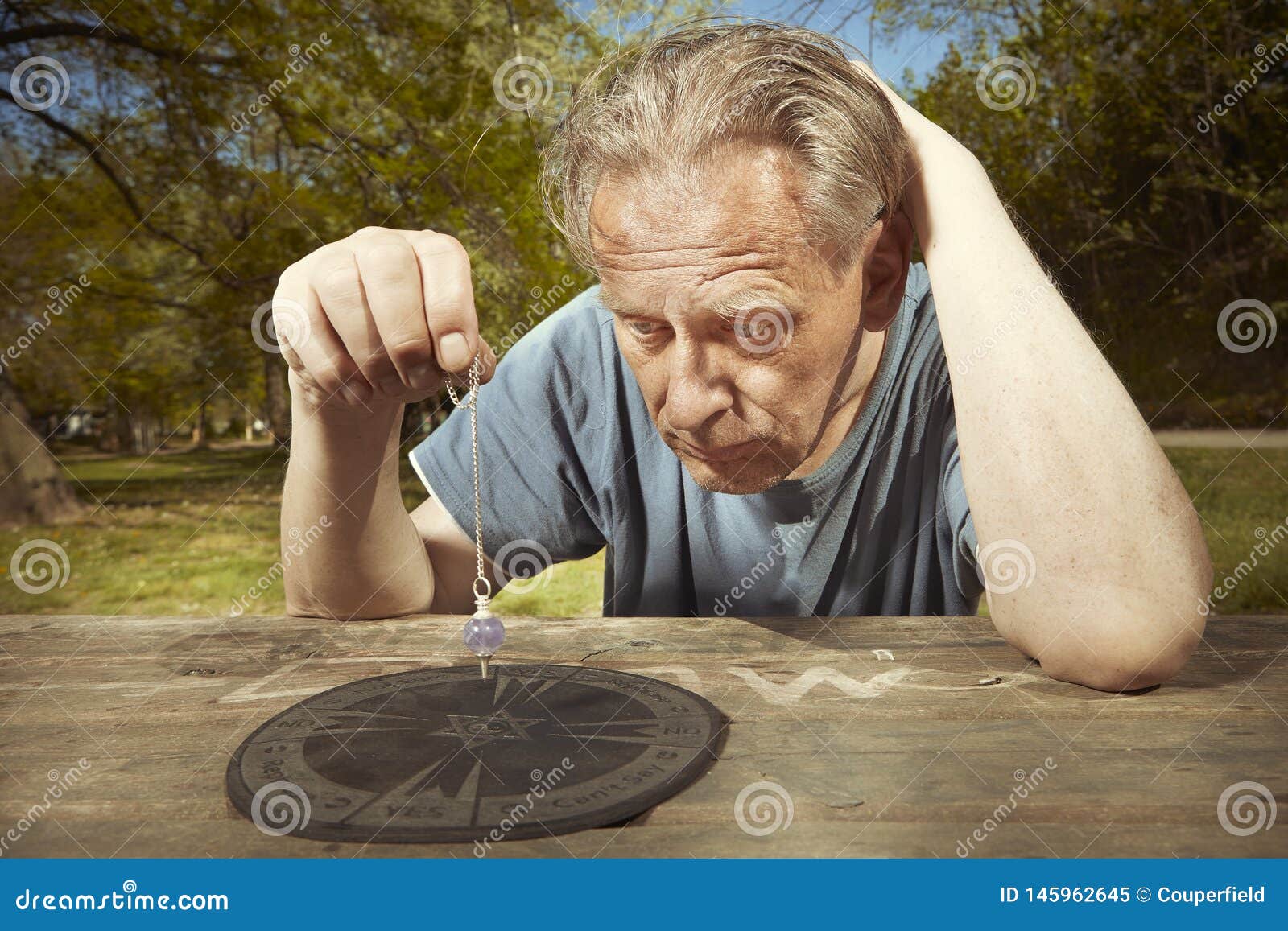 Aging Man Talking with Ghosts in Park with Pendulum and Table Stock ...