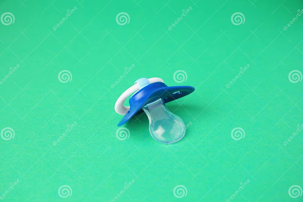 One Blue Baby Pacifier on Green Background Stock Image - Image of ...