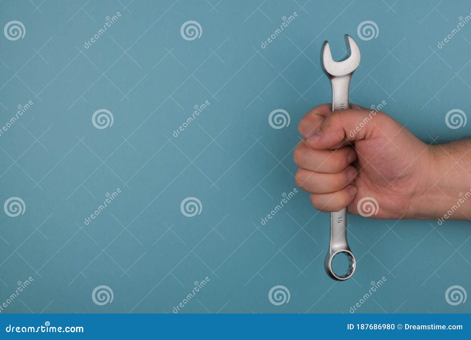 One Chrome Spanner Keys in Mans Hand on Blue Background. Minimal ...