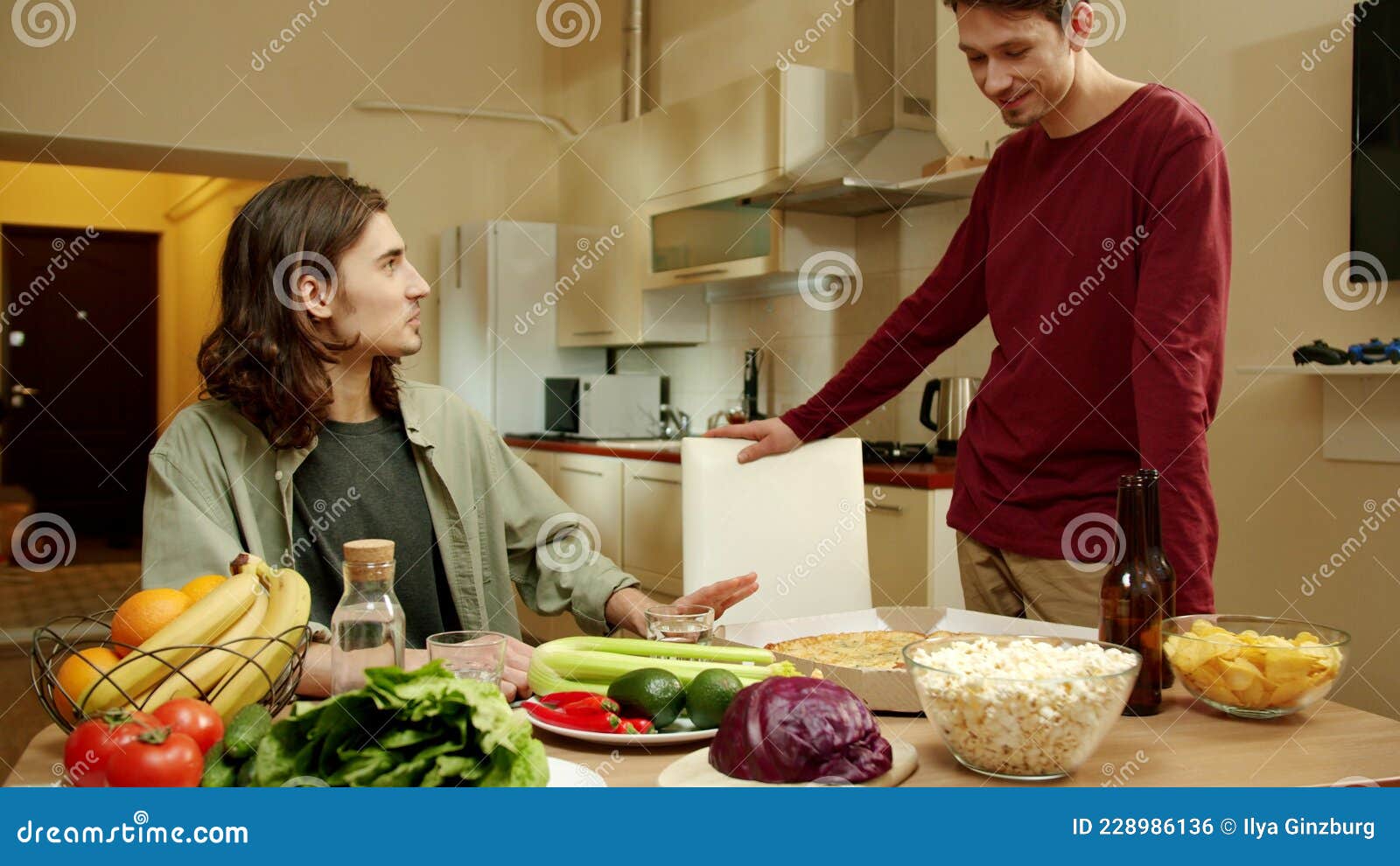 One of Friends is Sitting Down at the Table while His Pal is Entering ...