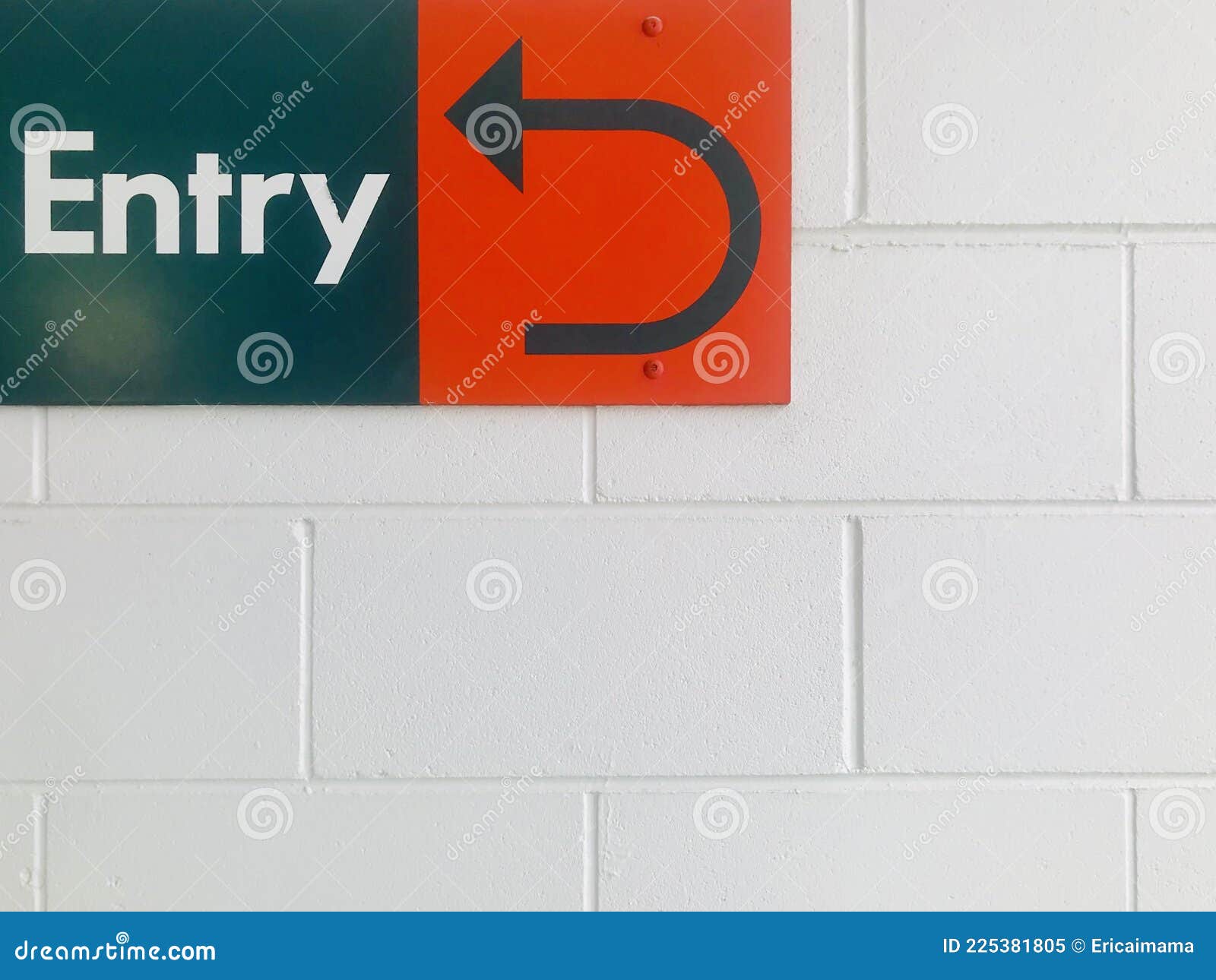 A Green Entry Sign with a Red Arrow Indicates on White Brick Wall ...