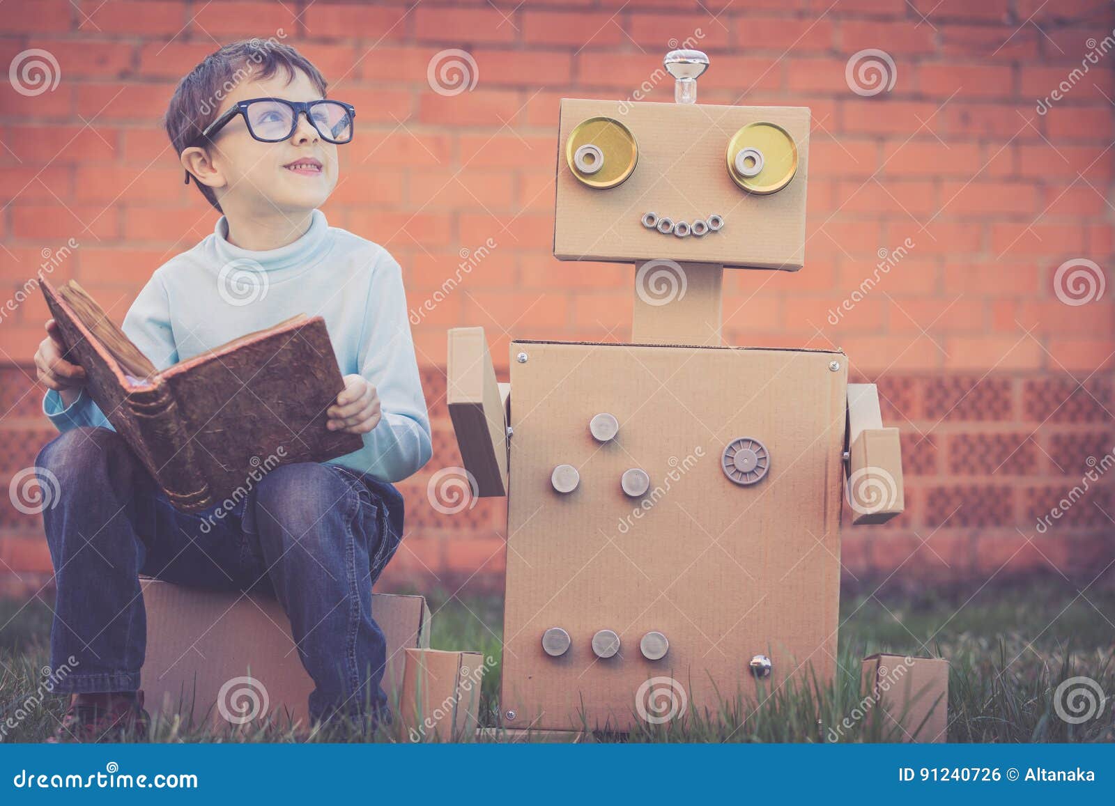One Little Boy Reading To Robot from Cardboard Boxes Outdoors. Stock ...
