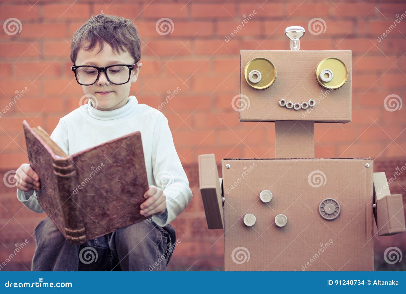 One Little Boy Reading To Robot from Cardboard Boxes Outdoors. Stock ...