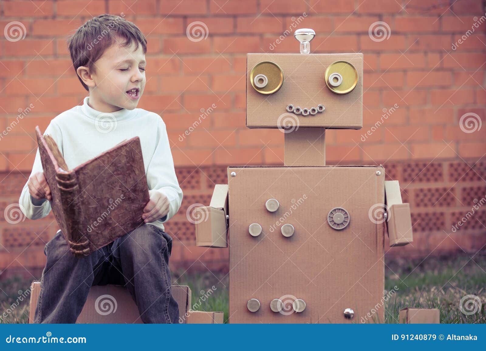 One Little Boy Reading To Robot from Cardboard Boxes Outdoors. Stock ...