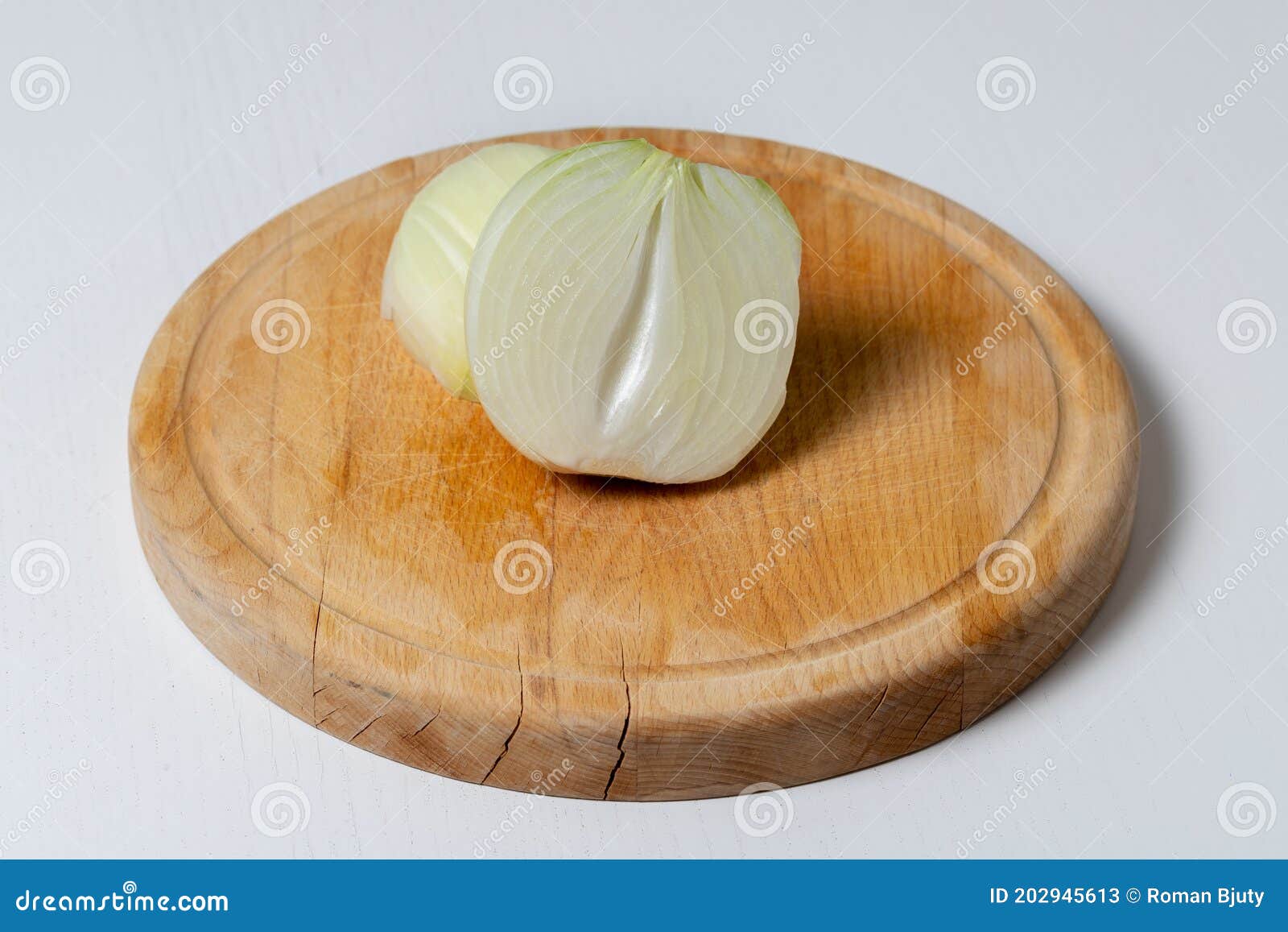 The Onion is Cut in Half on a Brown Wooden Board. the Cutting Board is ...