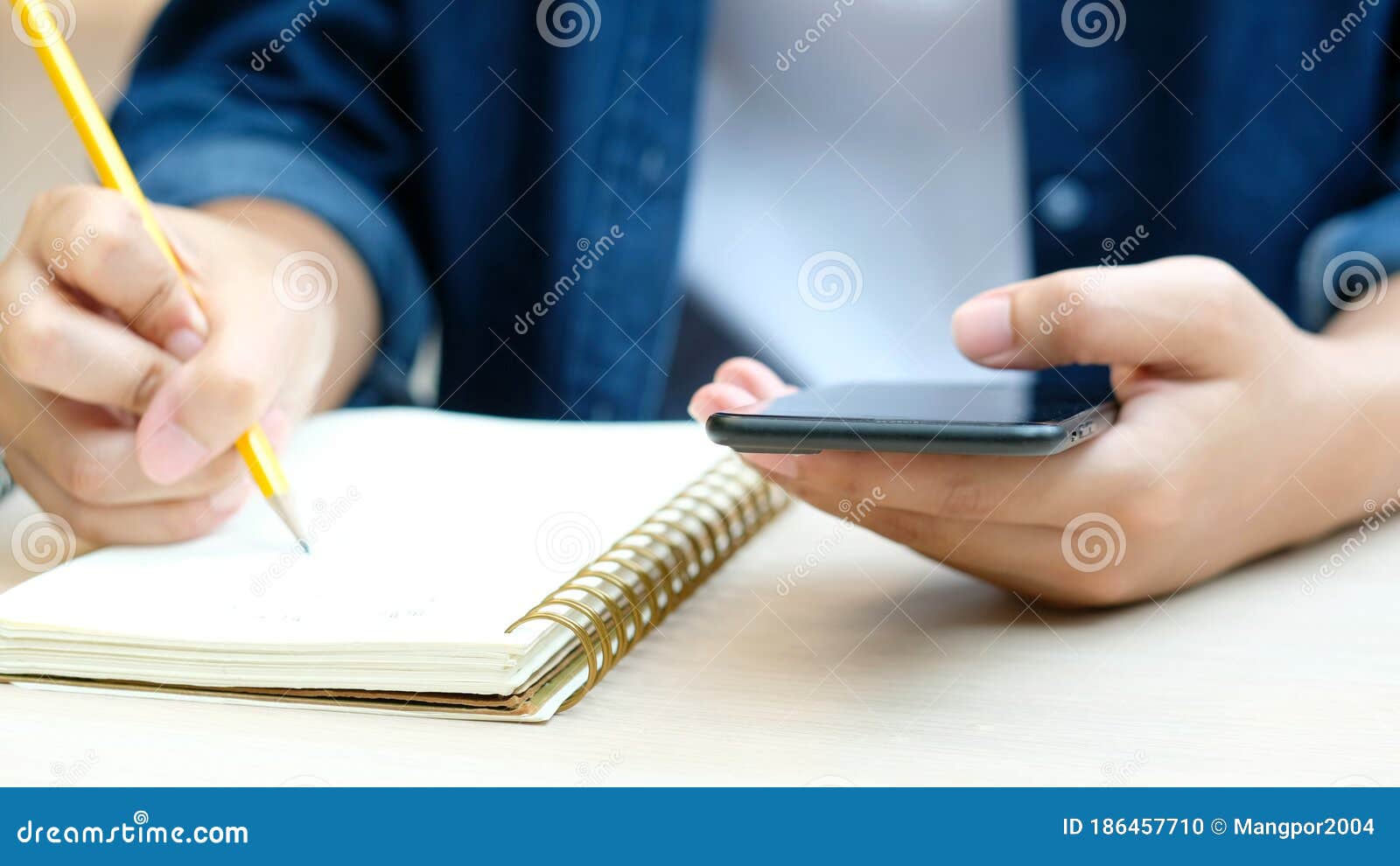 Online Study, Student Hand Writing on Notebook while Using Mobile Phone ...