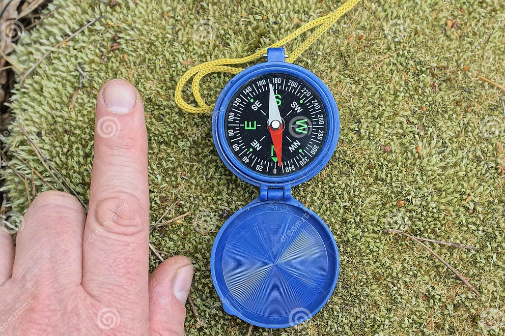 An Open Blue Plastic Compass and a Finger Pointing Direction Stock ...