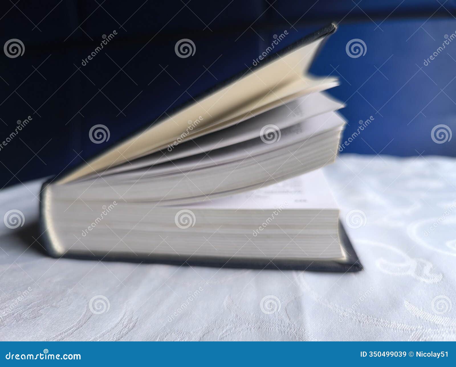 An Open Book Lying on a White Tablecloth Stock Image - Image of frame ...