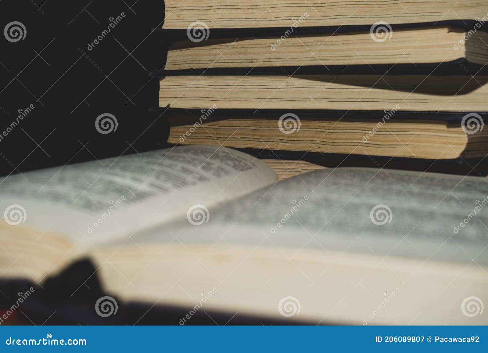 An Open Book with Pages and Text Out of Focus, a Stack of Books in the ...