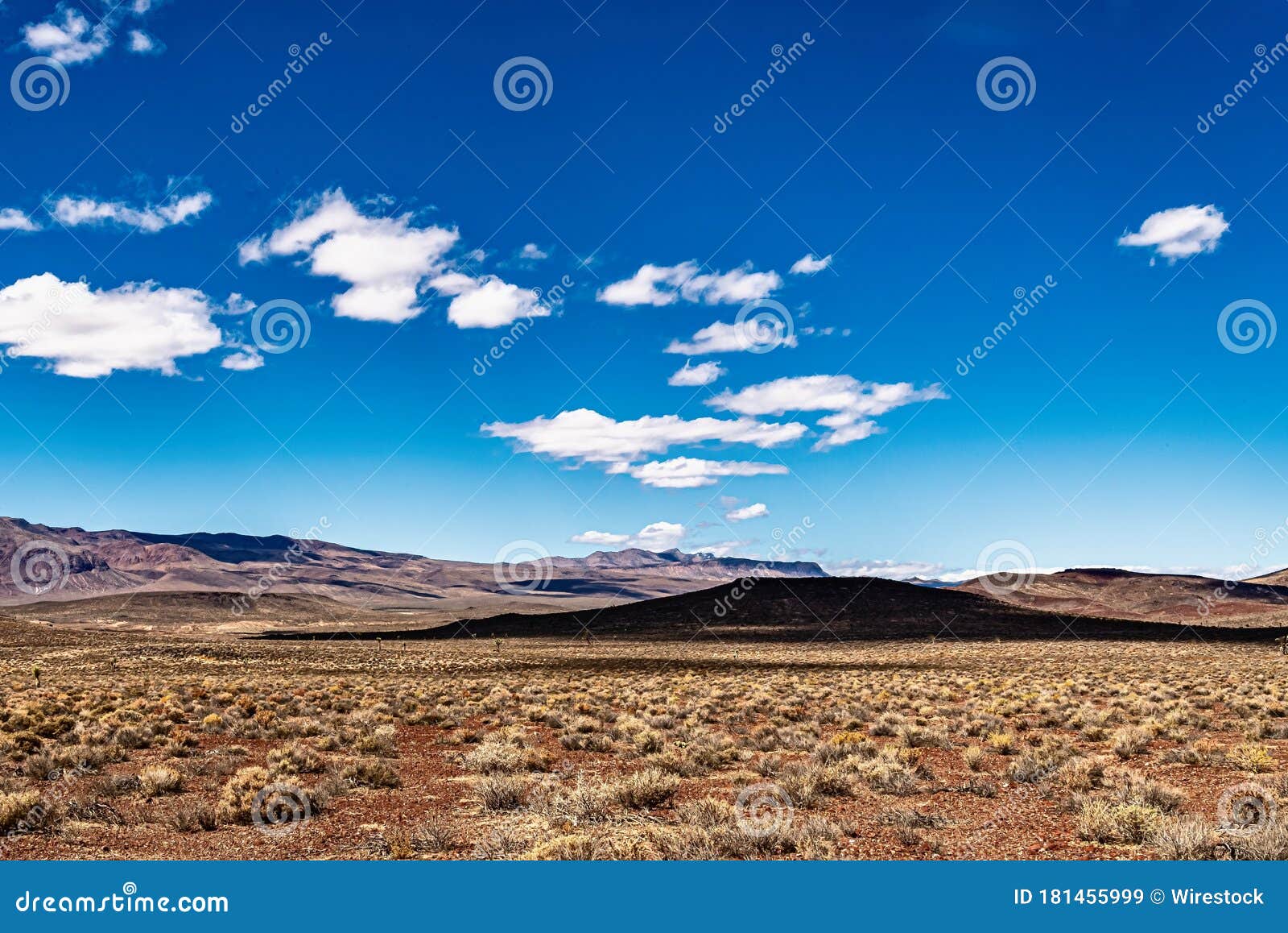 Open Desert Field with Mountains and a Cloudy Blue Sky in the ...