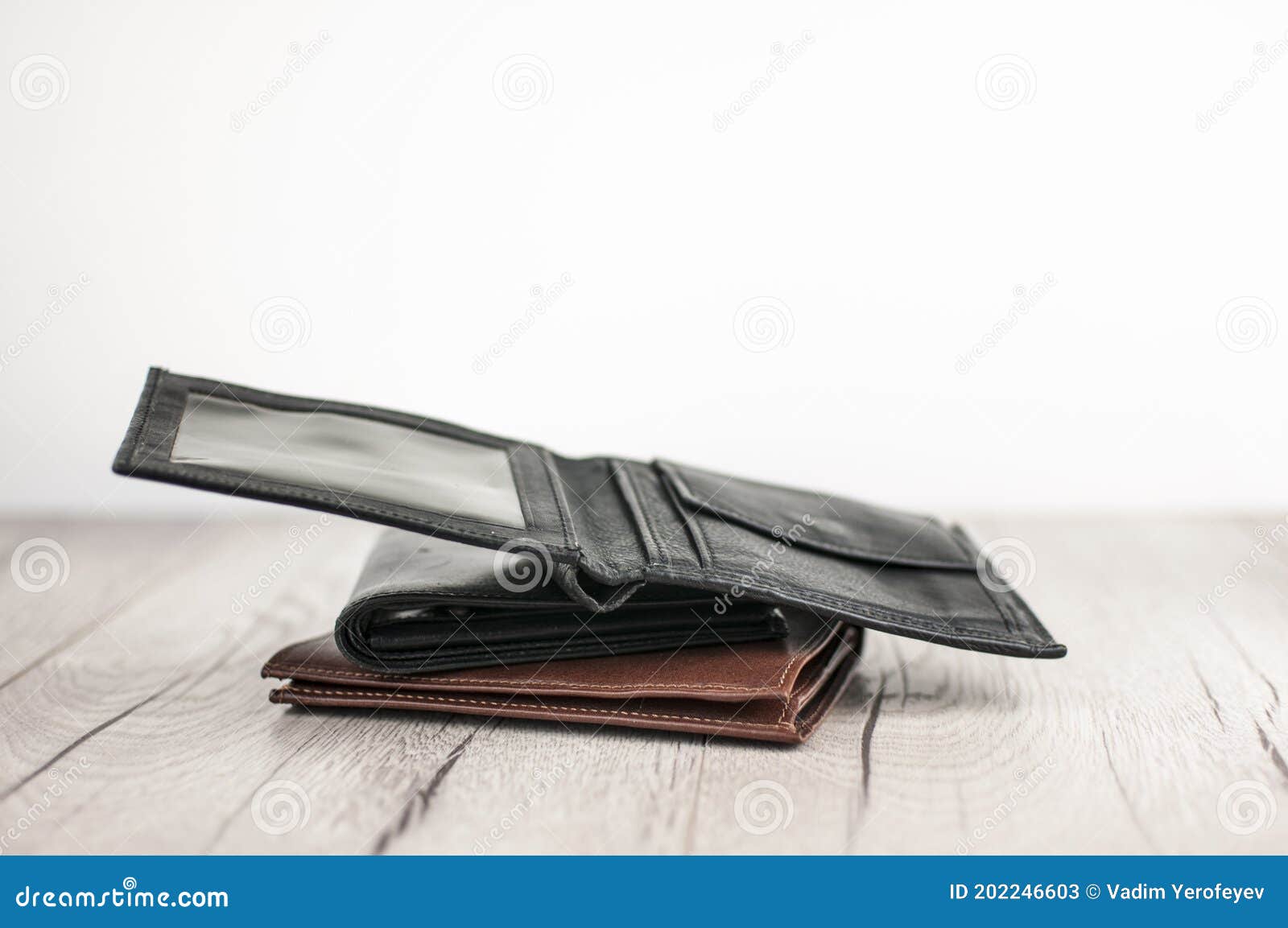 Open Leather Wallet on Stacks of Leather Wallets Over White Wood ...