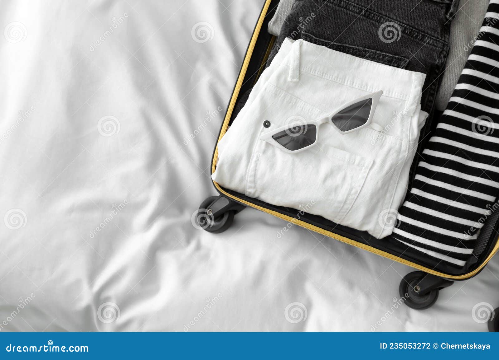 Open Suitcase with Clothes and Sunglasses on Bed, Top View. Space for ...