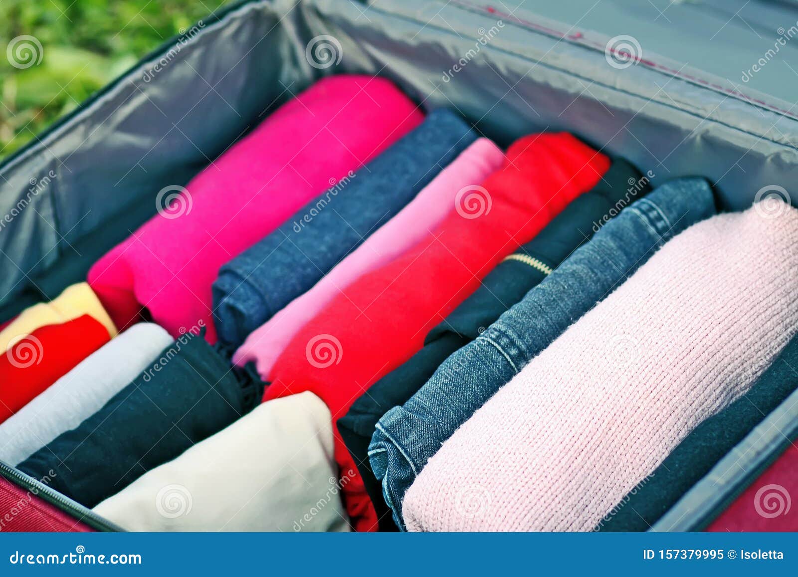 Open Suitcase on the Green Grass with Different Clothes Folded ...