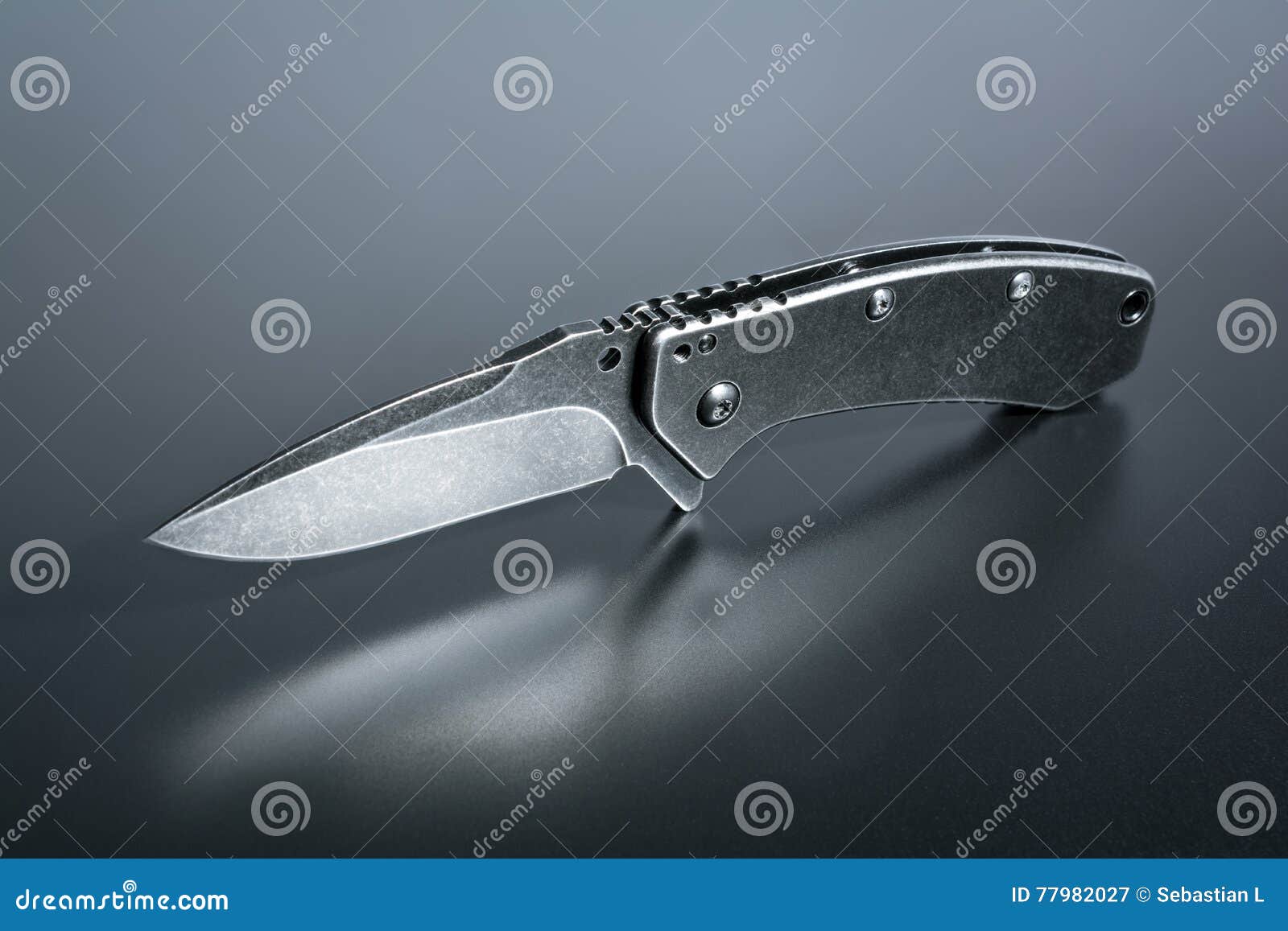 An Opened Black Folding Knife Standing on Dark Ground with Reflection ...