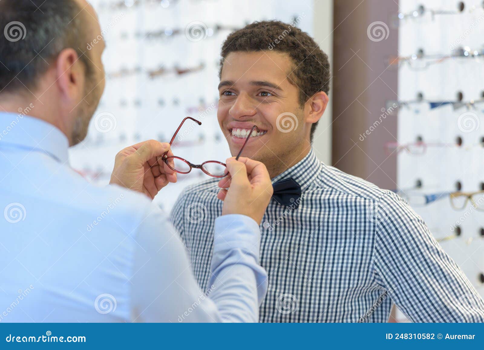 Optician Fitting Eyeglasses on Smart Young Man Stock Photo - Image of ...
