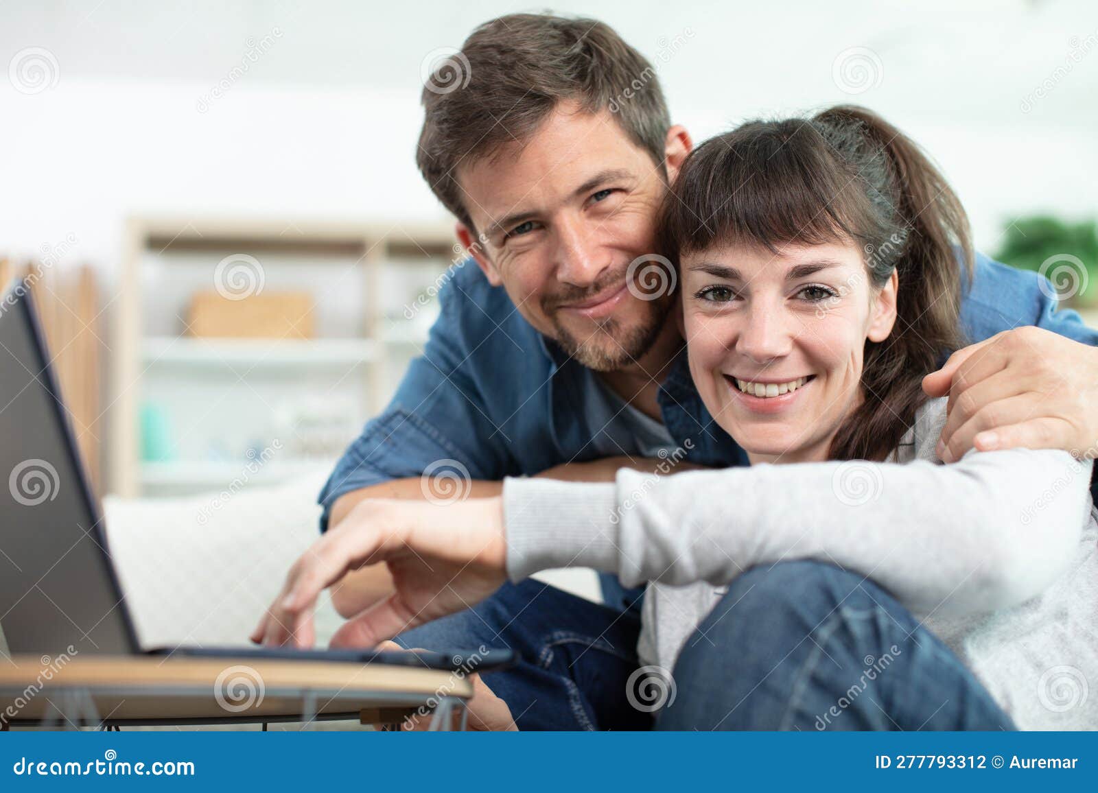 Optimistic Hugging Young Loving Couple Near Sofa Using Laptop Computer ...
