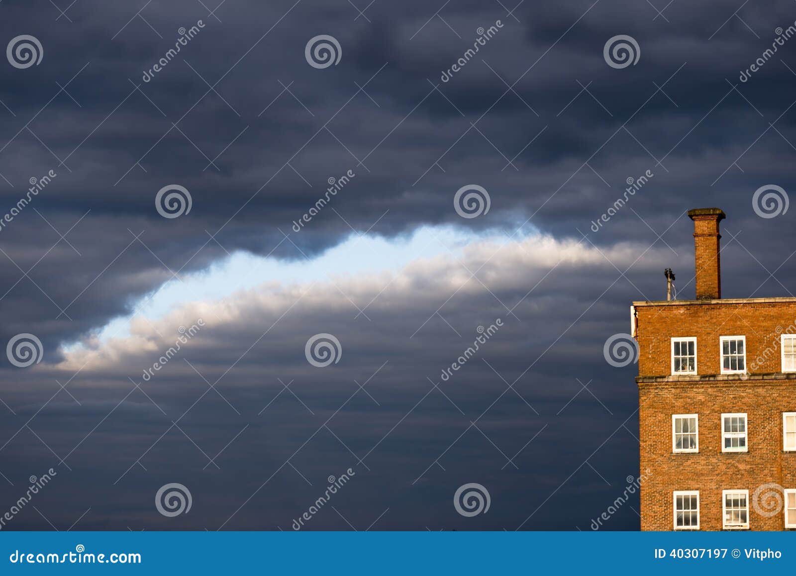 Orange Brick Building with Windows on a Dark Cloudy Sky Stock Image ...