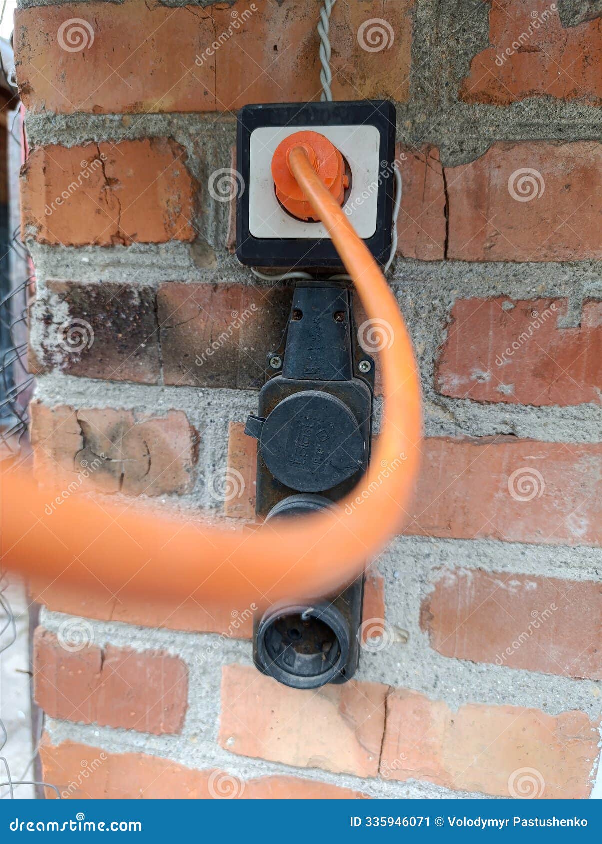 An Orange Cable Connected To an Electrical Outlet on a Brick Wall Stock ...