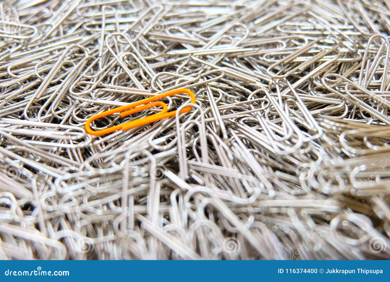 Orange Paper Clip on Multiple Paper Clips Background. Stock Photo ...
