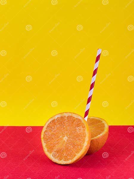 Orange Split in Half with a Straw Simulating a Soft Drink on a Yellow ...