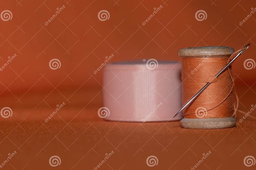 Orange Threads on a Wooden Spool with a Needle on a Background of ...