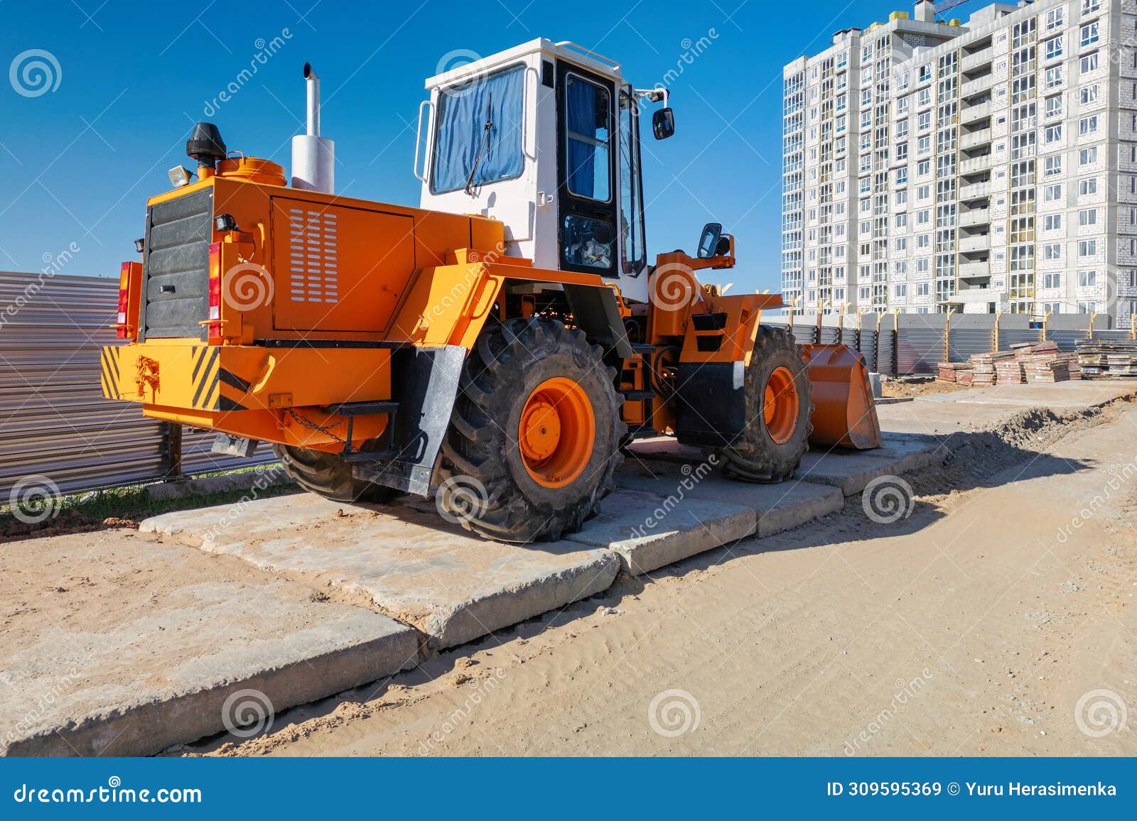 An Orange and White Construction Vehicle is Stationed on the Side of a ...