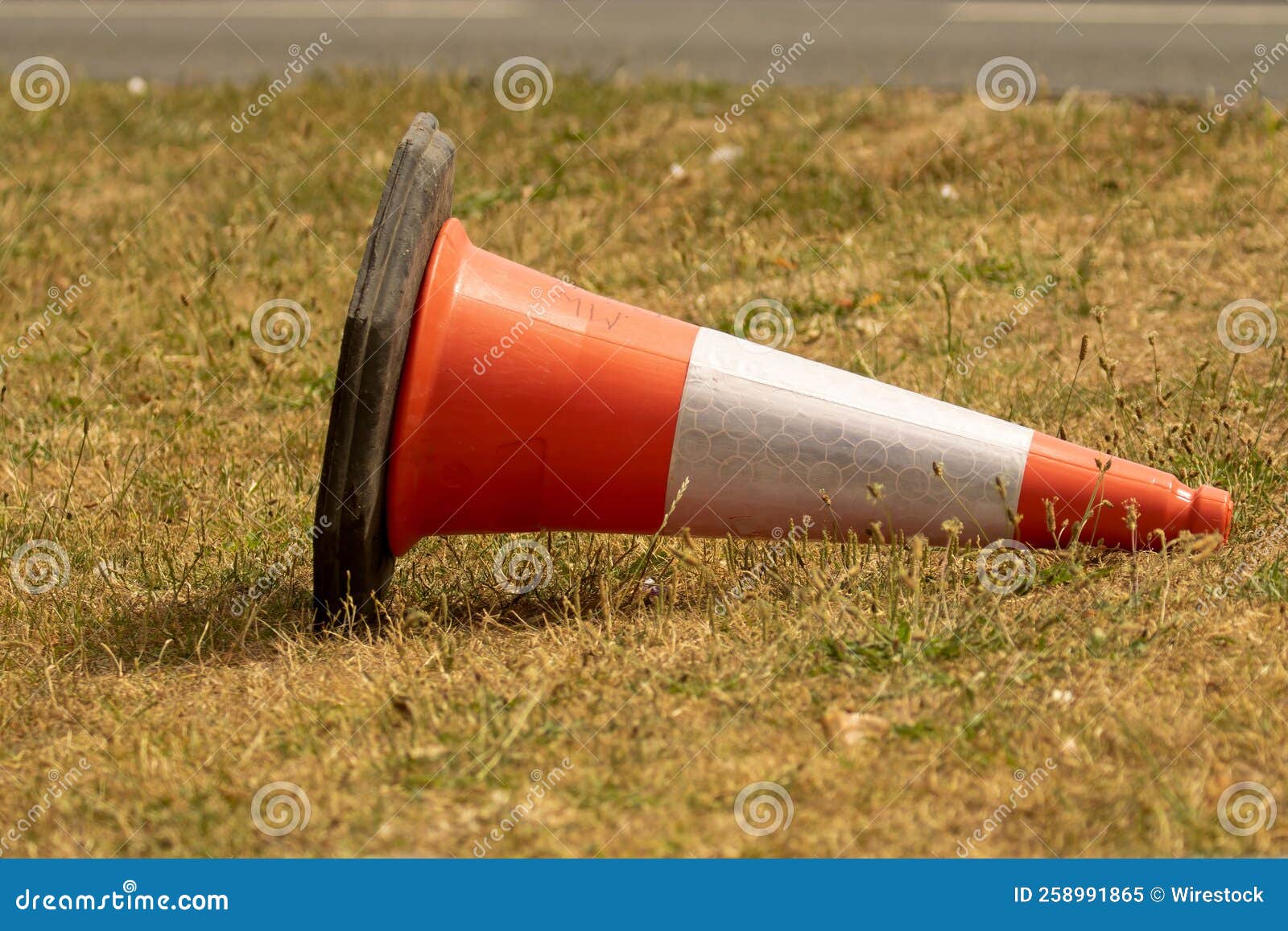 Orange and White Traffic Cone Laying on Side on Grass Verge with Road ...